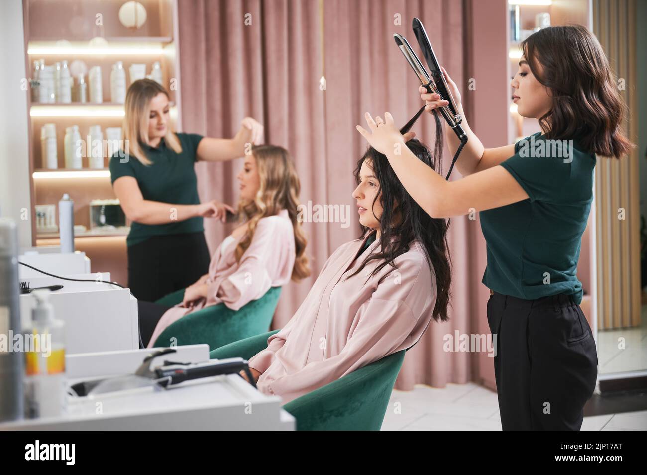 Female hairstylist curling client hair with curling iron device while ...