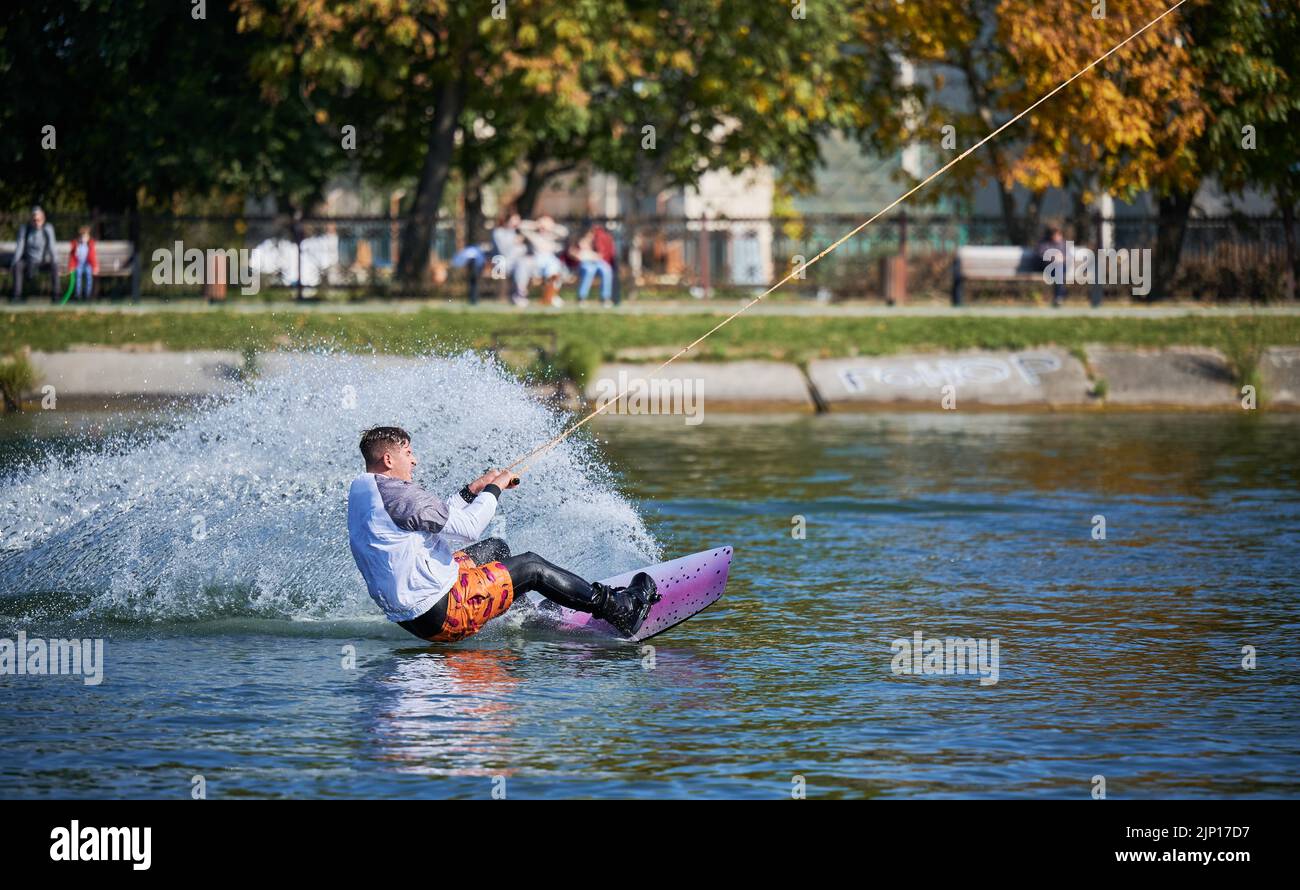 Wakeboarder surfing on lake. Young man surfer having fun wakeboarding ...