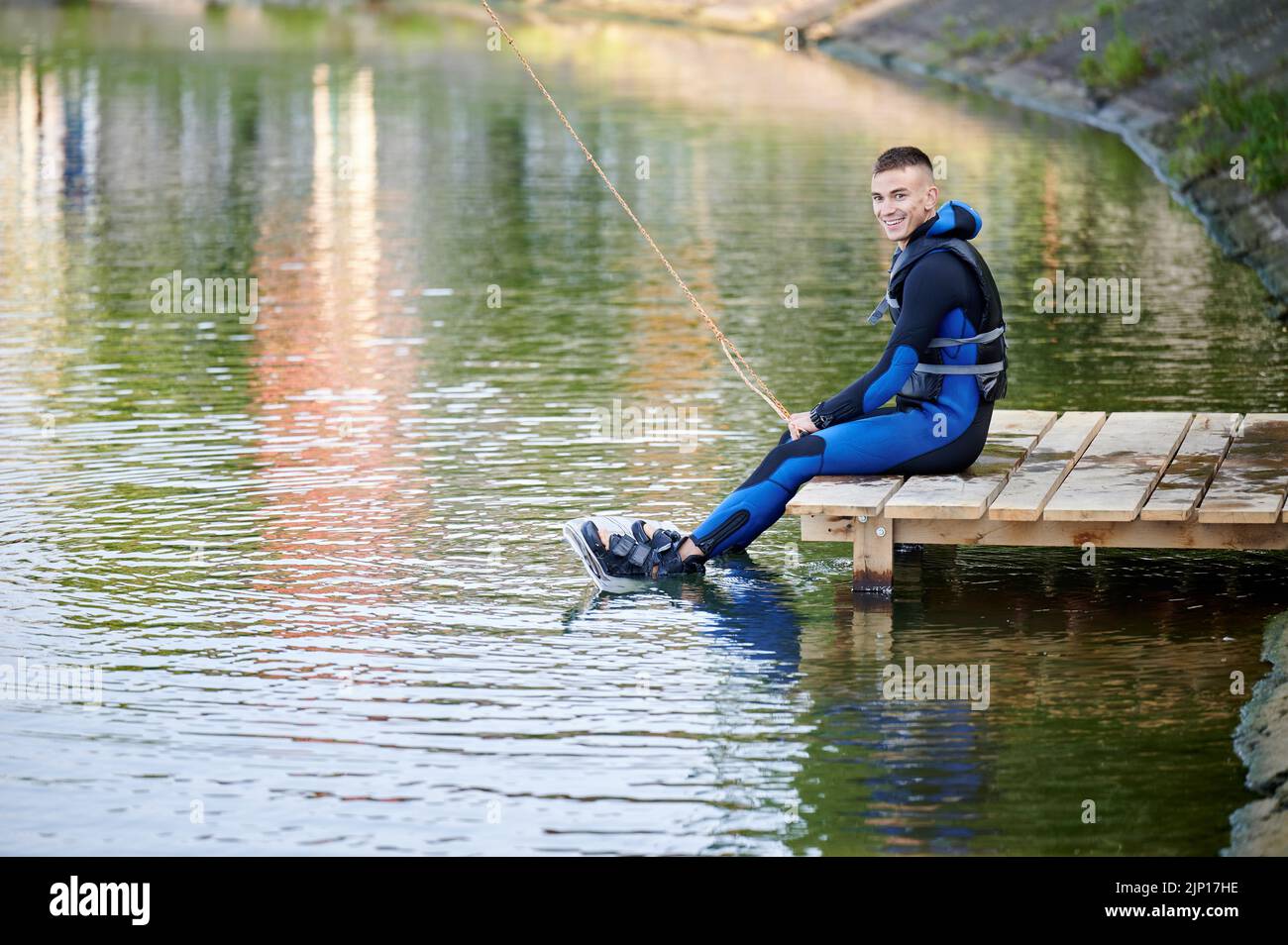 Wakeboarder making ready of surfing on lake. Young surfer having fun ...