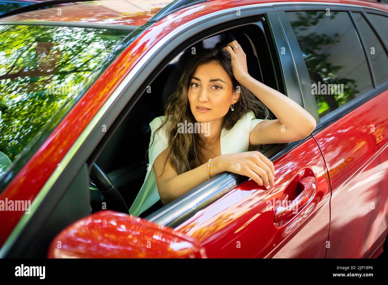 Happy smiling woman driver behind the wheel red car. View through car ...