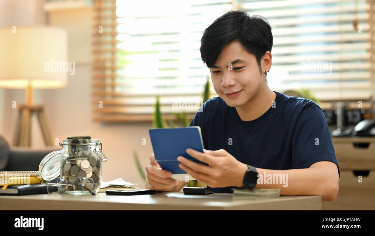 Asian man calculating household finances or taxes on calculator ...