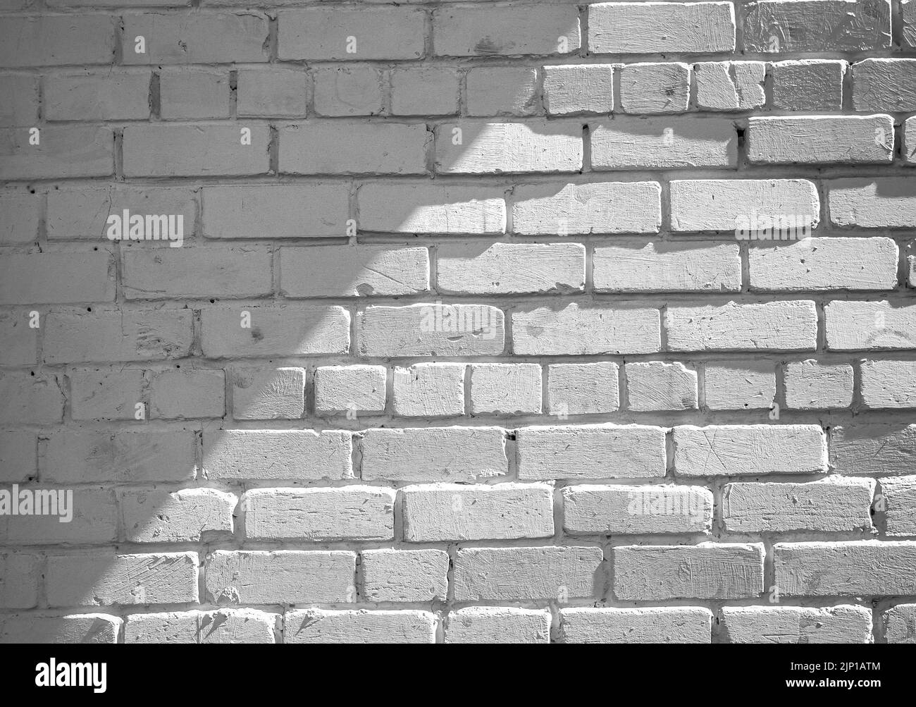 white brick wall is lit by the sun from side, an oblique shadow falls ...