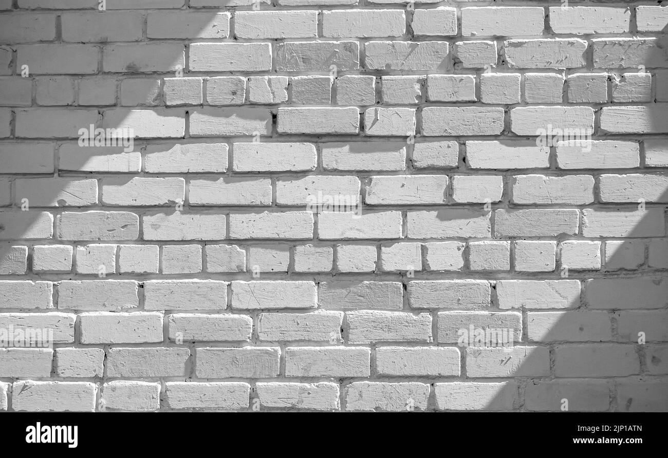white brick wall is lit by the sun from side, an oblique shadow falls ...