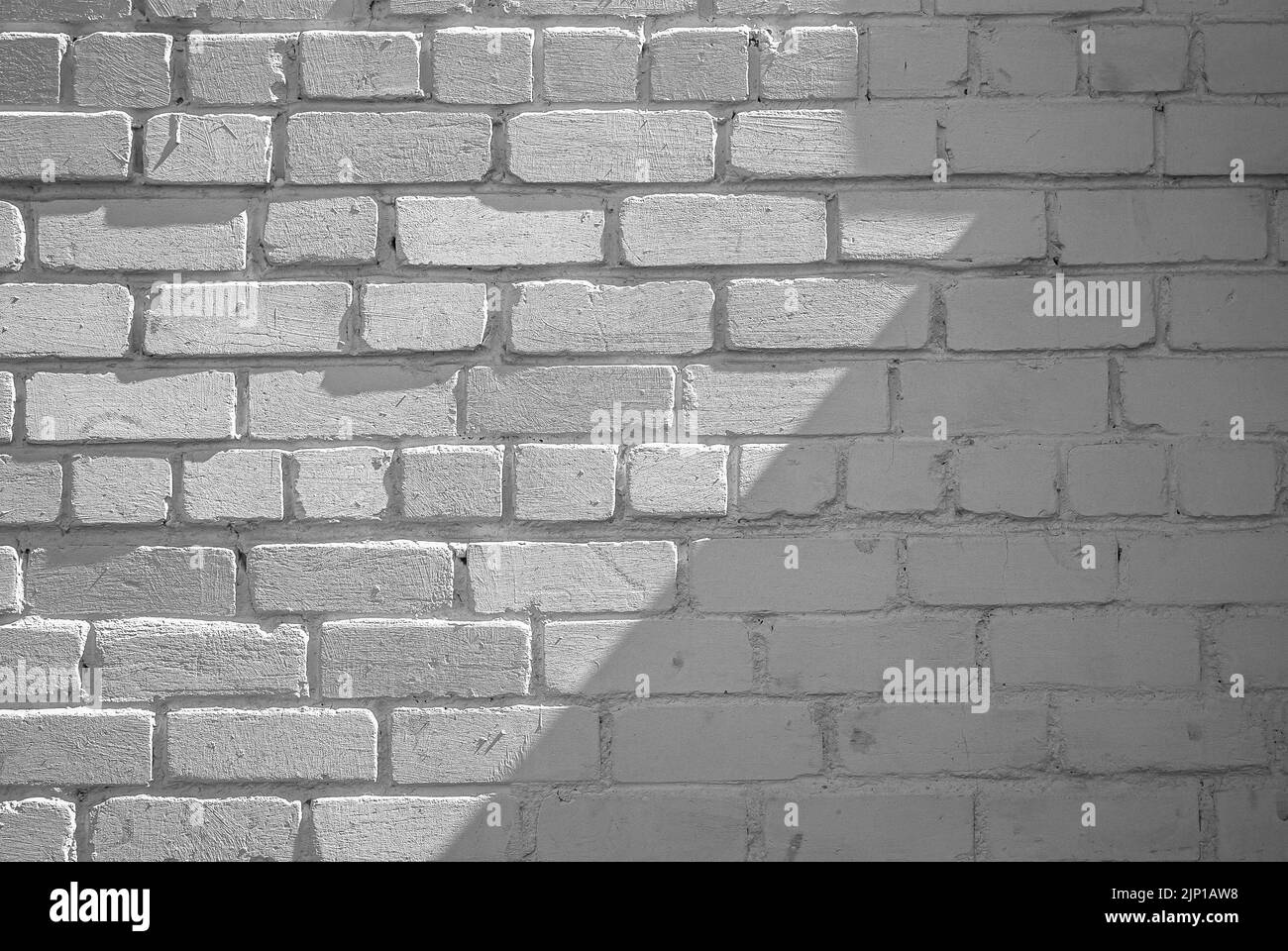 white brick wall is lit by the sun from side, an oblique shadow falls ...