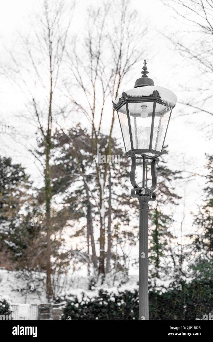 Retro classic snow-covered street light with modern electric balb in ...