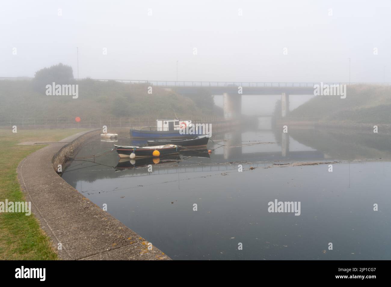 Boats in heavy sea fret at the harbour, at high tide in Seaton Sluice ...