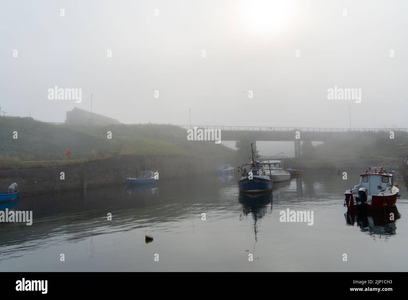 Boats in heavy sea fret at the harbour, at high tide in Seaton Sluice ...