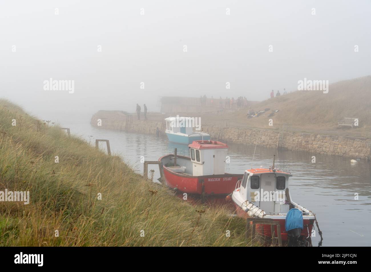 Boats in heavy sea fret at the harbour, at high tide in Seaton Sluice ...