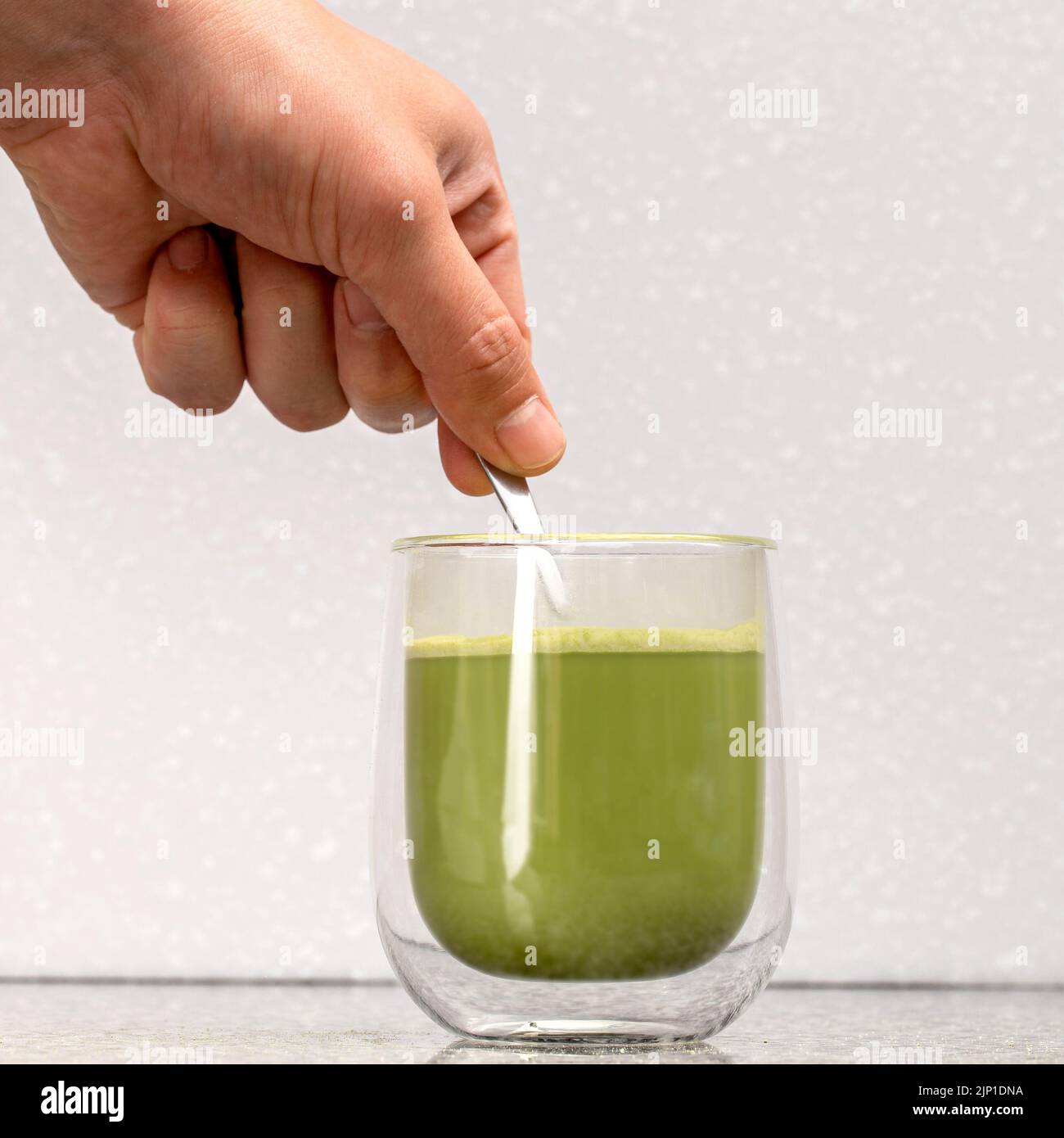 Green matcha latte tea in a glass. Green matcha latte is poured into a ...