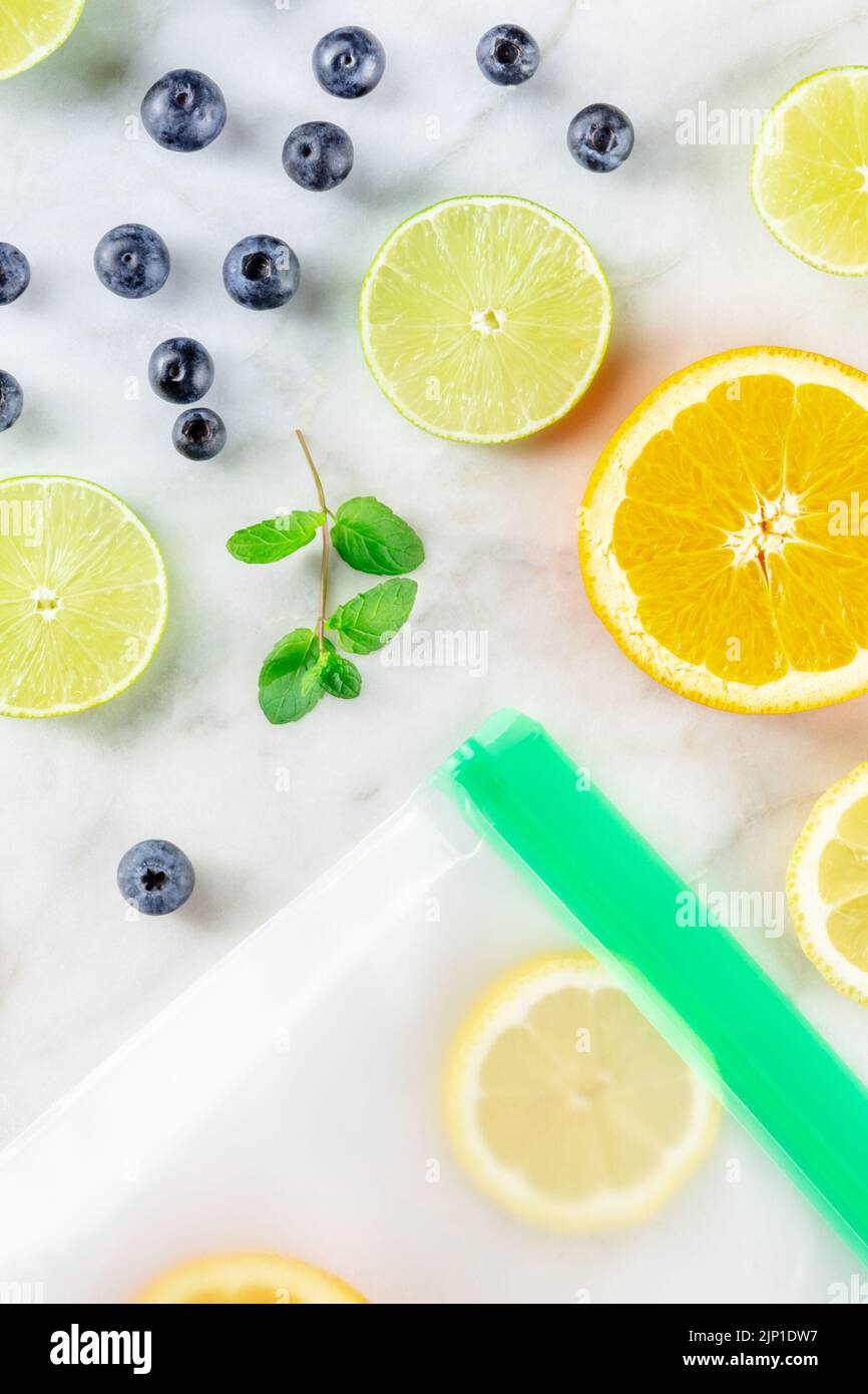 Reusable food storage bags with fresh fruit, top shot on a white marble ...