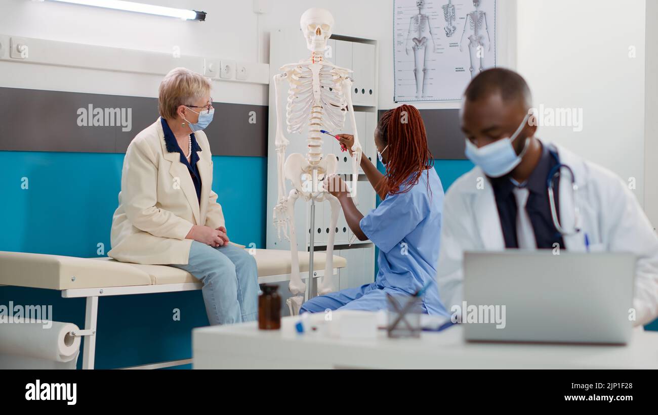 Old woman and nurse with face masks analyzing human skeleton bones at ...