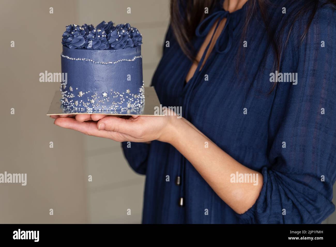 Pastry chef holding a small cake. Smiling young female holding cupcake ...