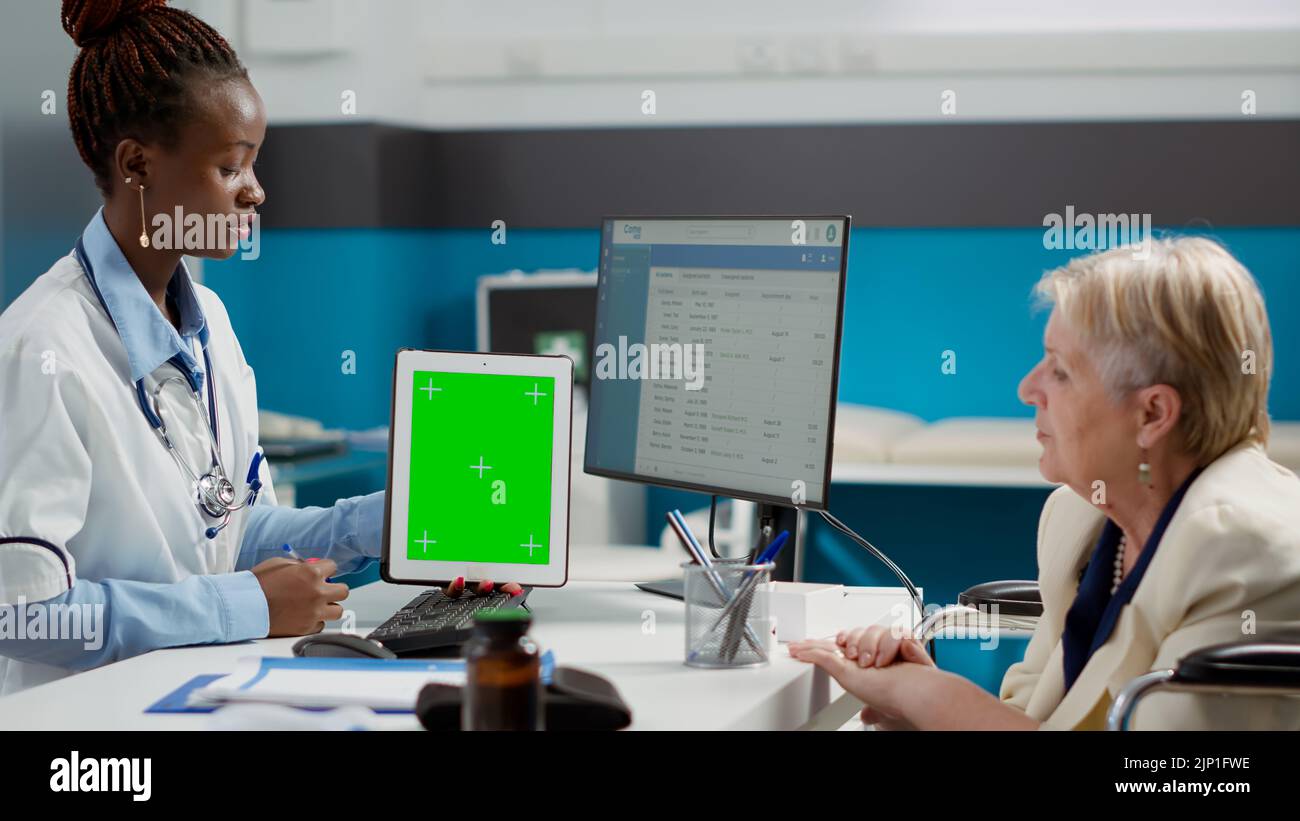 Health specialist showing greenscreen on tablet to woman with ...