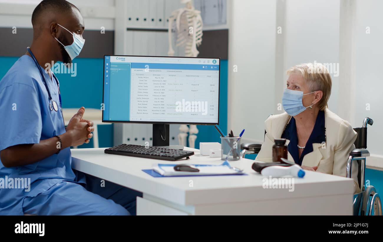 African american nurse doing consultation with patient in wheelchair ...