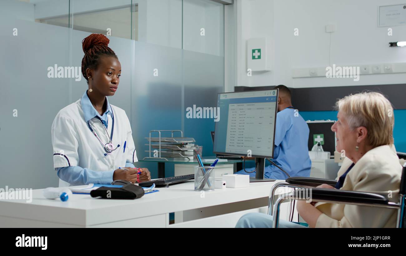 African american doctor consulting woman with physical disability in ...