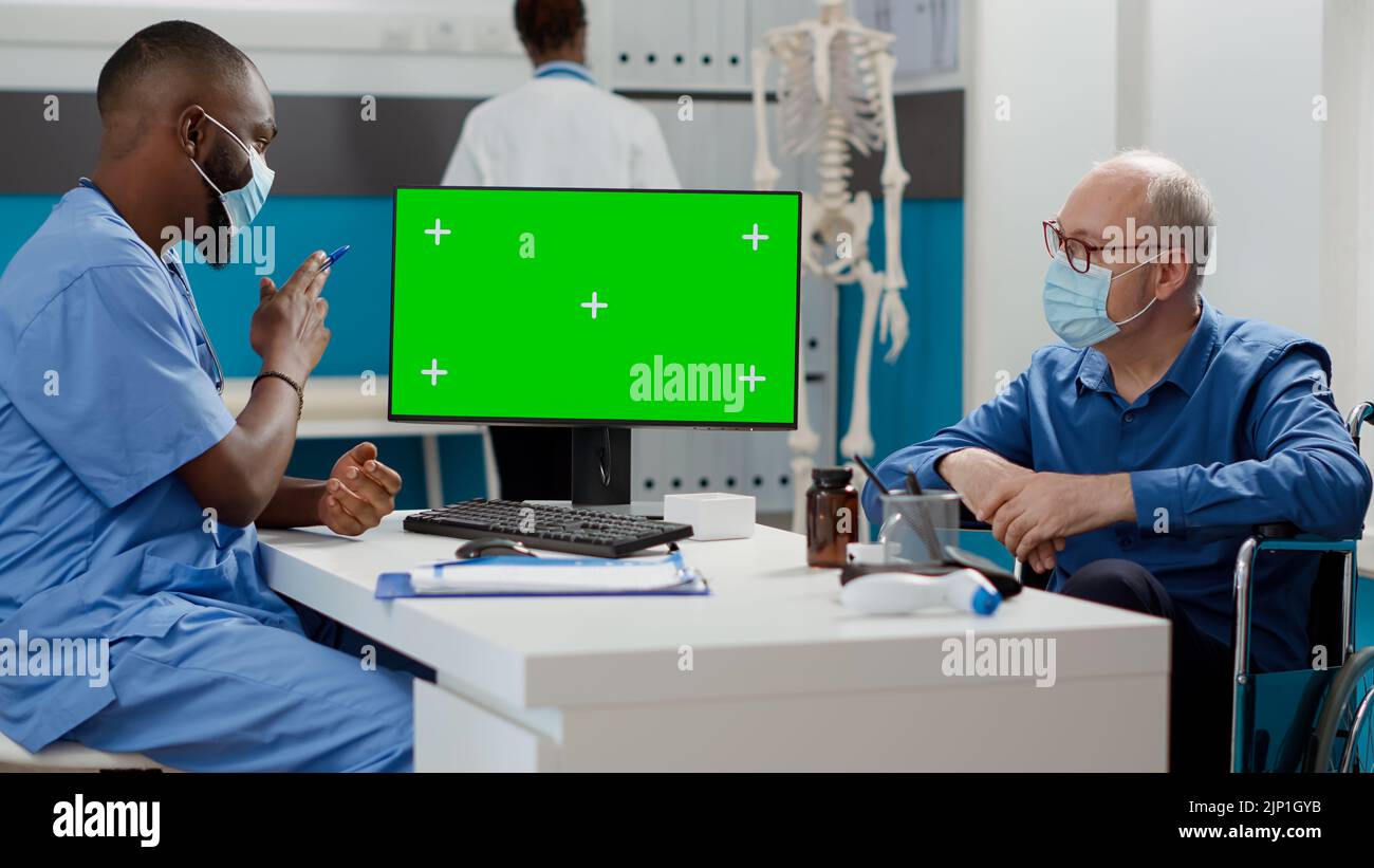 Specialist and old man looking at monitor with greenscreen, dealing ...