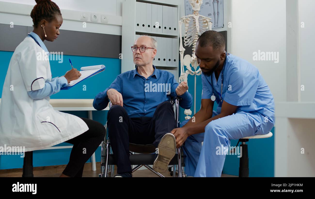 Doctor and nurse consulting patient with chronic impairment, doing ...