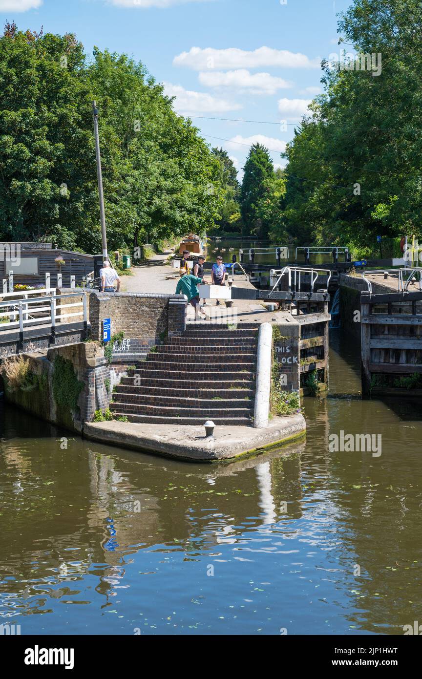Young woman and two boys watch man closing lock gate for narrow boat to ...