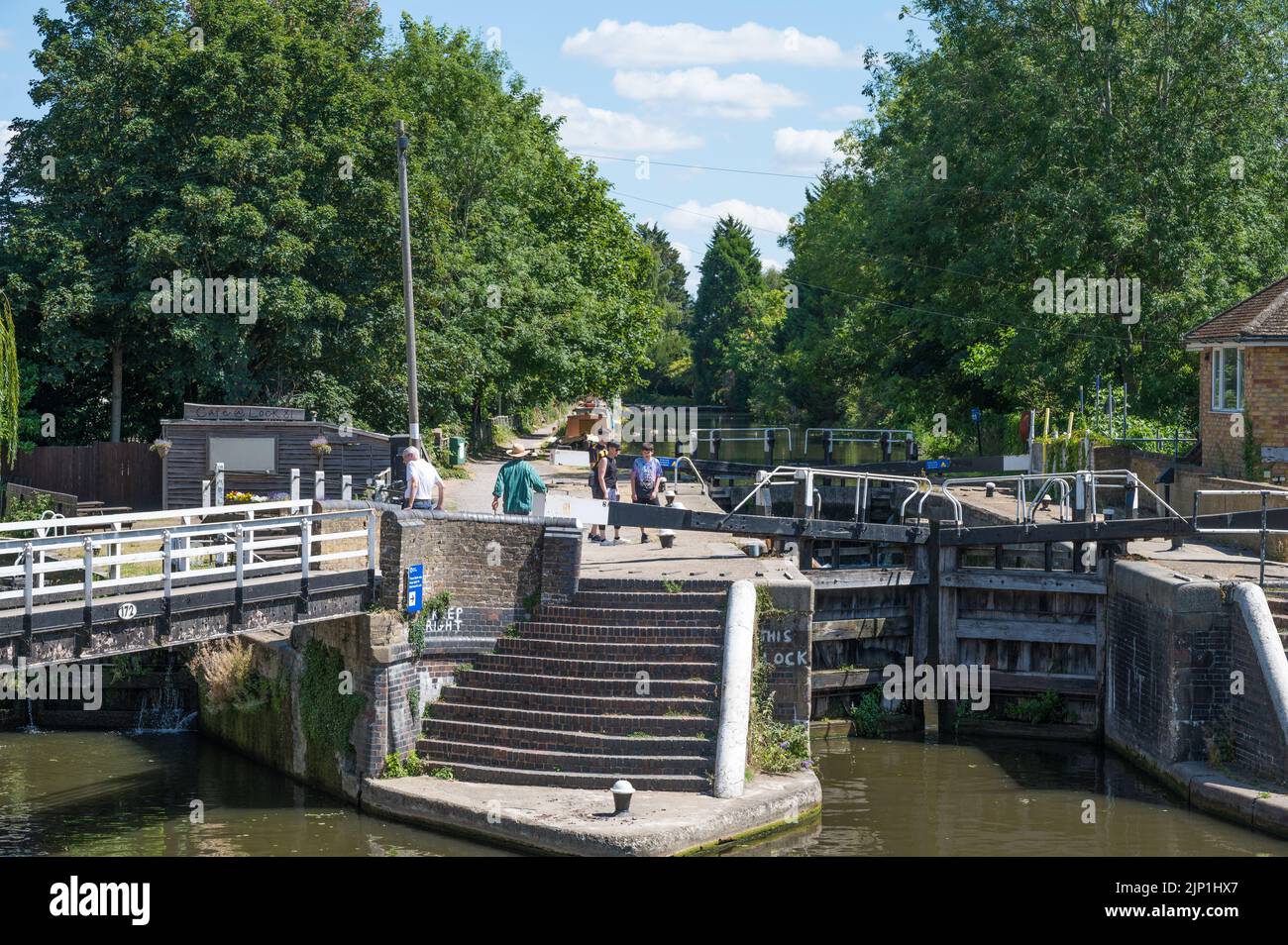 Young woman and two boys watch man closing lock gate for narrow boat to ...