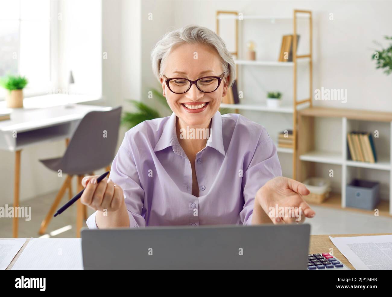 Friendly senior business woman consults with her clients using laptop ...