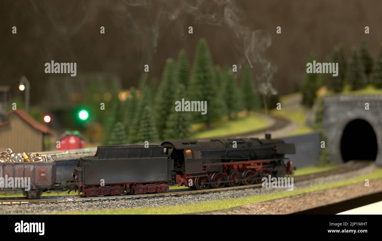 Toy train with smoke moving on model railway. Black model of locomotive ...