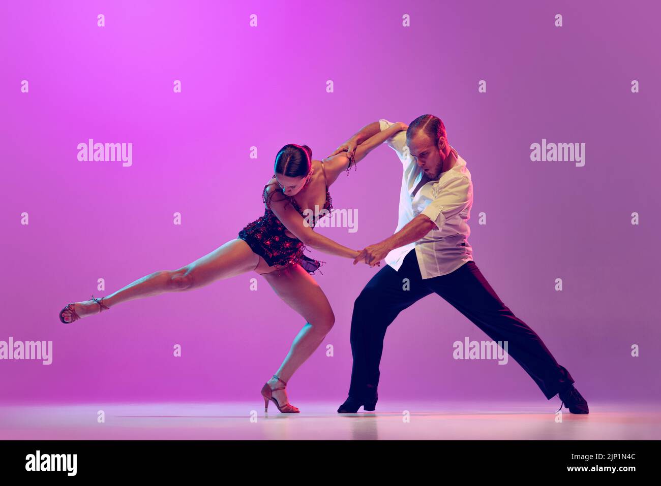 Two young graceful dancers wearing stage outfits dancing ballroom dance ...