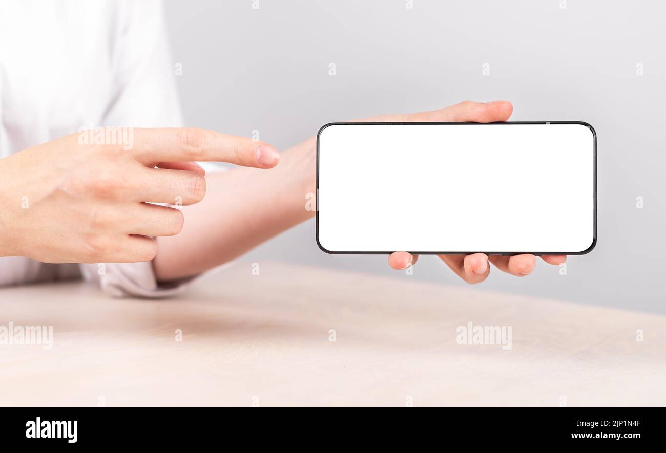 Woman forefinger pointing to phone mockup in horizontal position ...