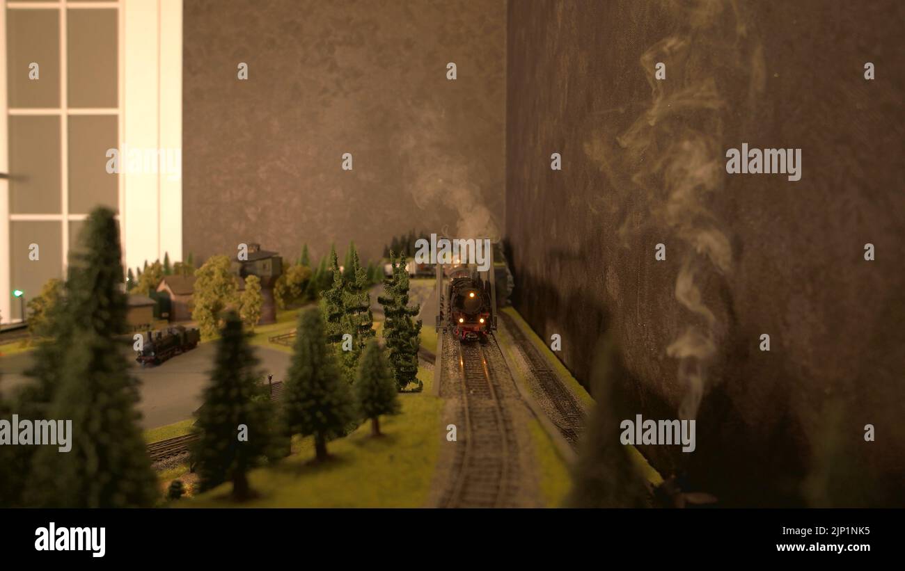 Front view of electric toy locomotive moving on railroad. Miniature ...