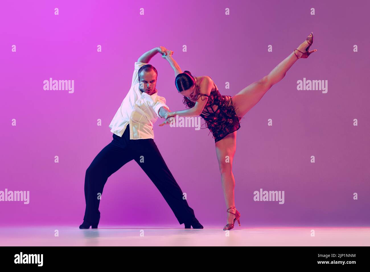 Two young graceful dancers wearing stage outfits dancing ballroom dance ...