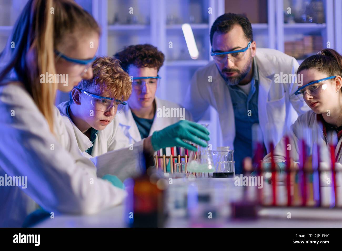 Excited science students with teacher doing chemical experiment in the ...
