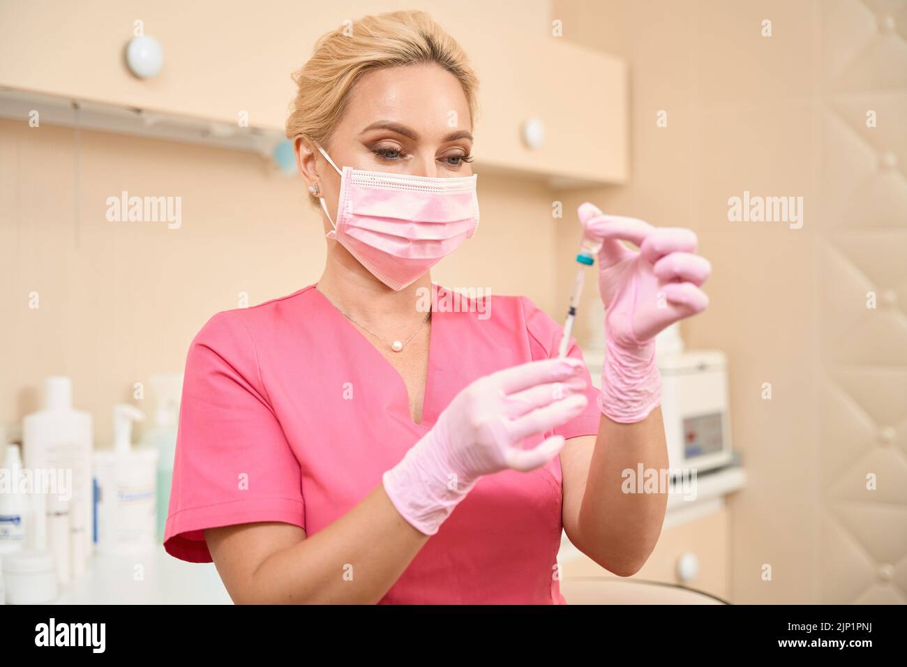 Beautiful woman beautician is drawing solution for injection into ...