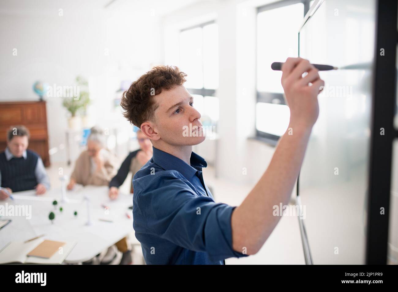 Young teacher writing on whiteboard during alternative energy lecture ...