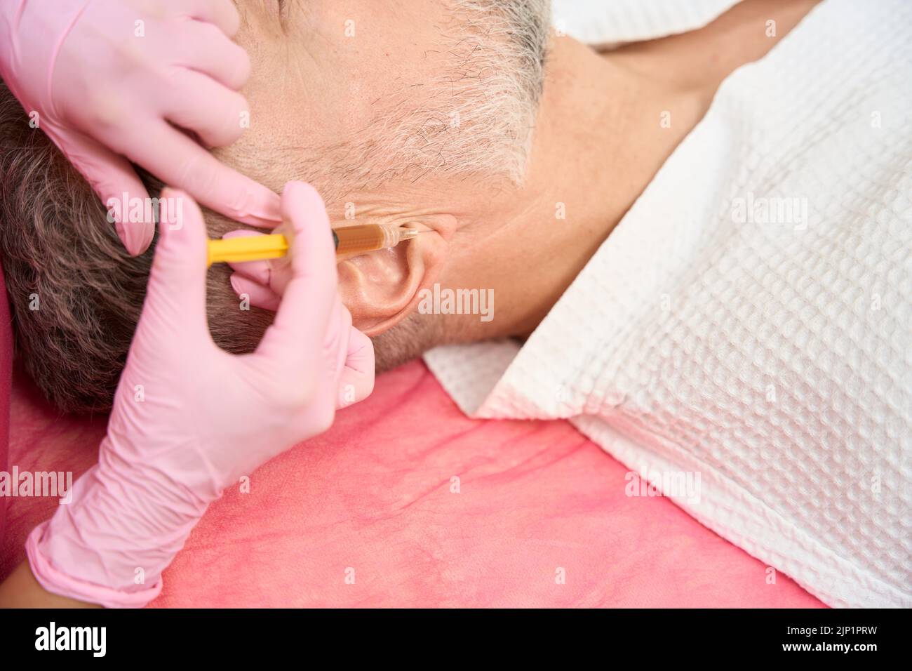 Female hands make beauty injection to man in earlobe Stock Photo - Alamy