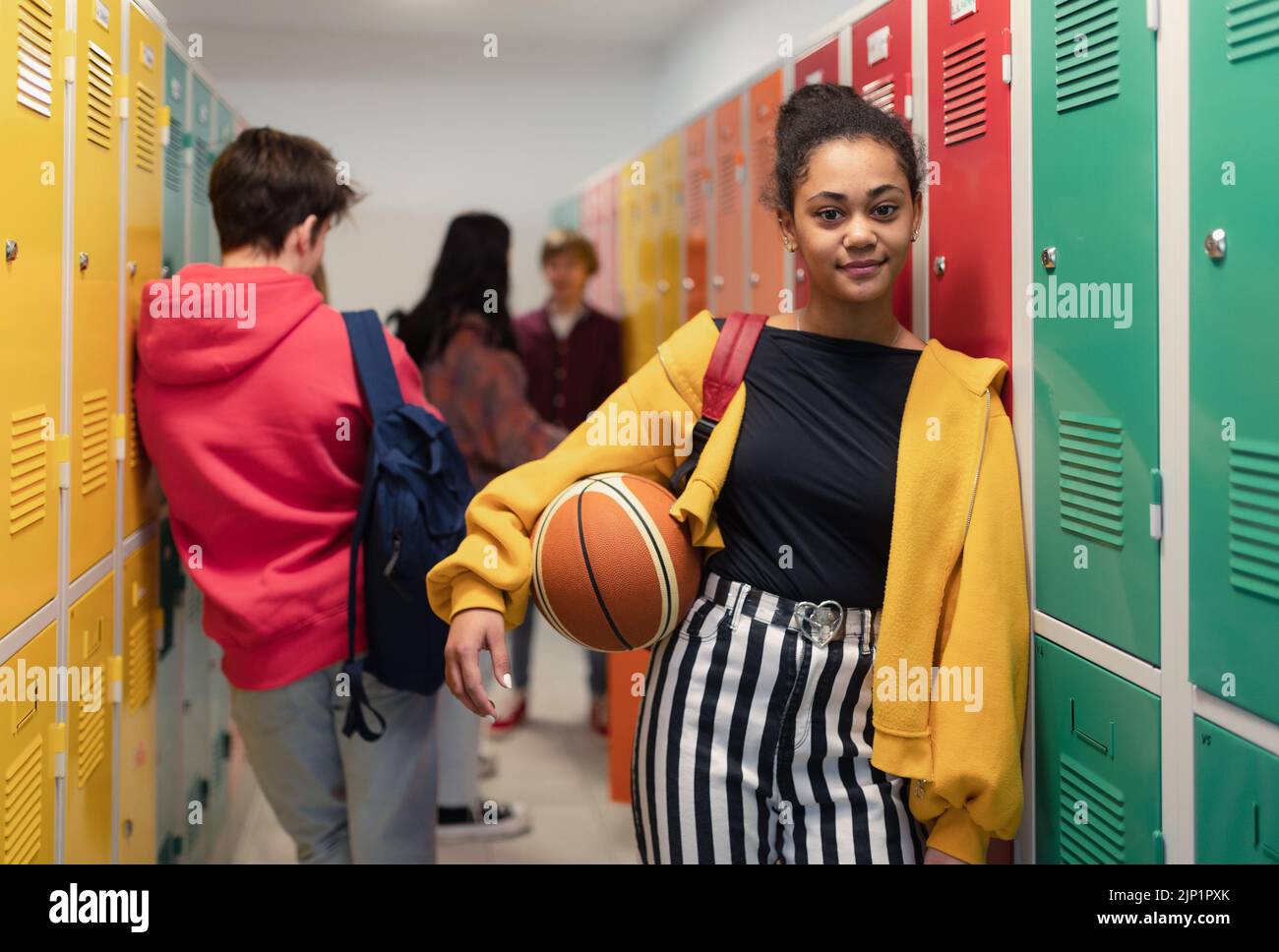 Young high school students meeting and greeting near locker in campus ...