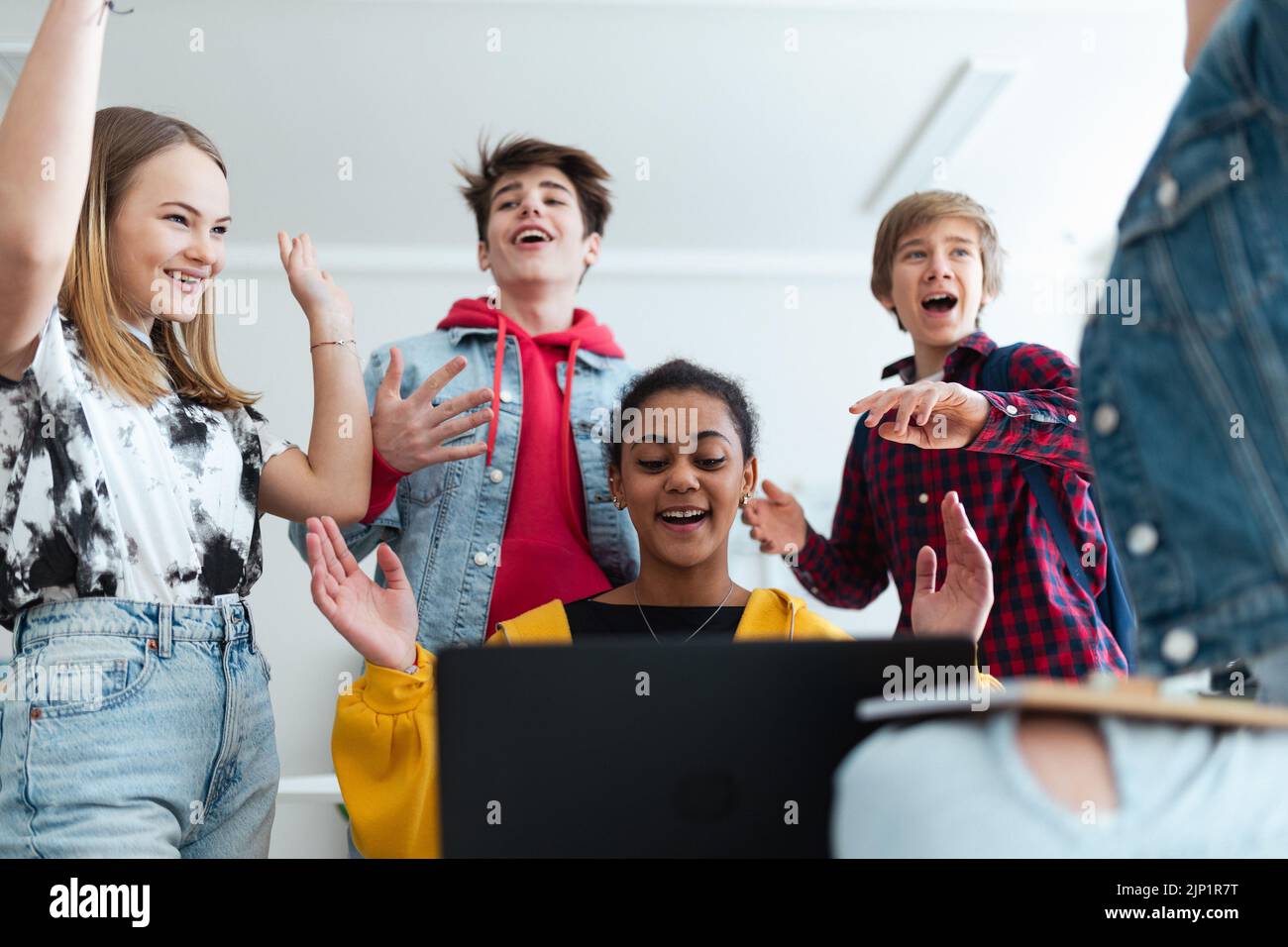 High school students sitting together at desk and using laptop and ...