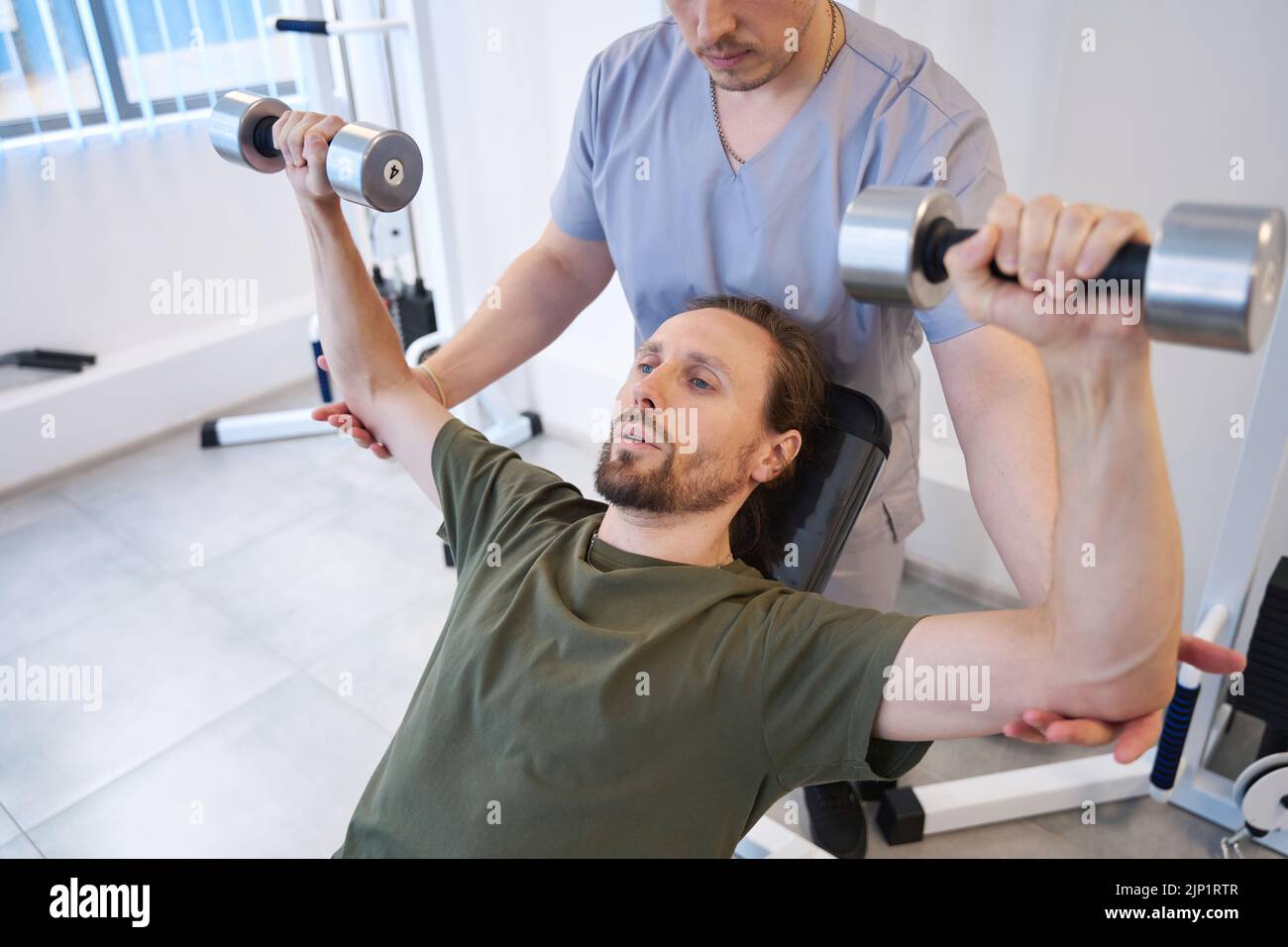 Patient performs exercises with dumbbells under the supervision of ...