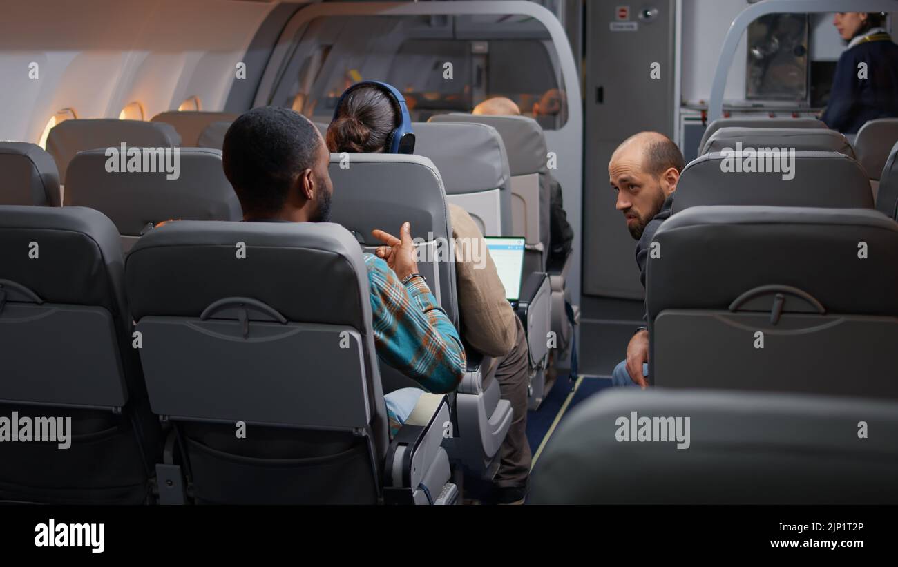 Diverse travellers having conversation in airplane before takeoff ...