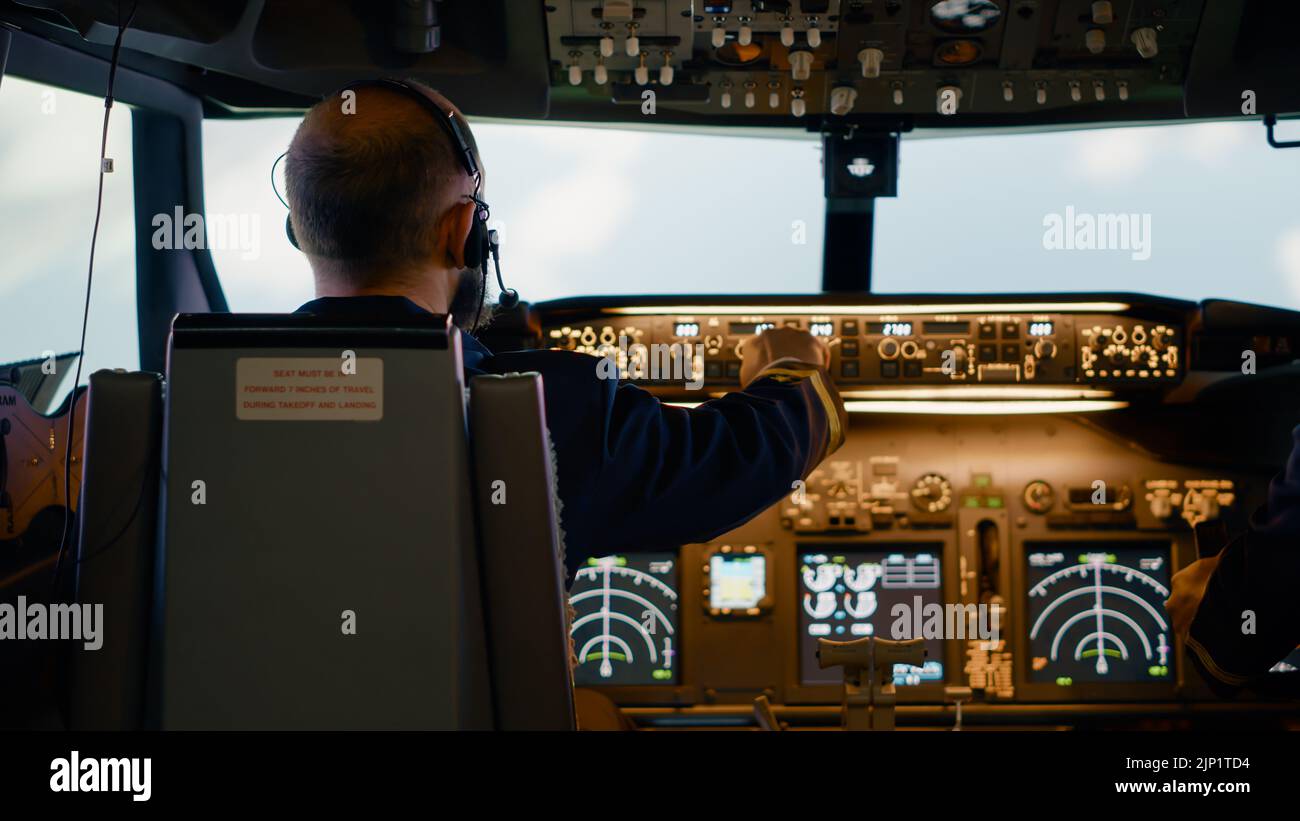 Male airline captain fixing altitude and longitude buttons, using dashboard navigation command ...