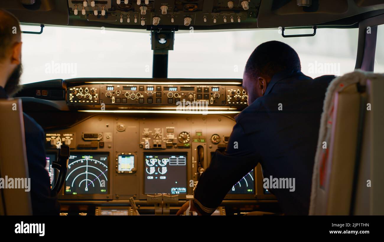 Diverse team of captain and copilot in cockpit flying airplane, using ...