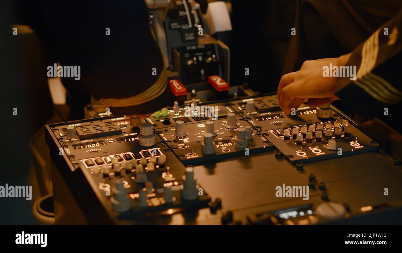 Captain and copilot pushing dashboard buttons to start engine, using airline navigation command ...