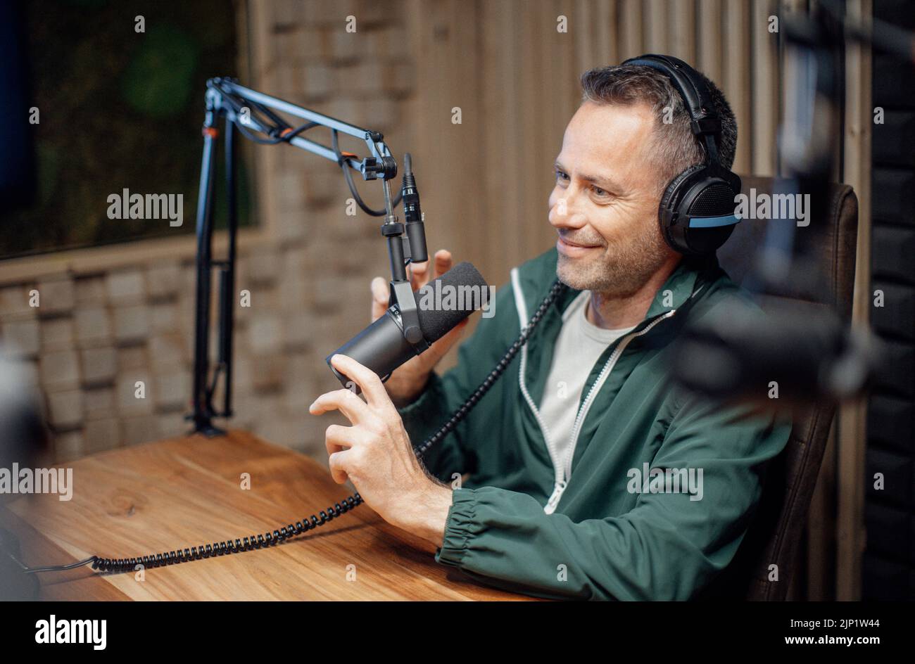 Portrait of mature radio host speaking in microphone while moderating a ...
