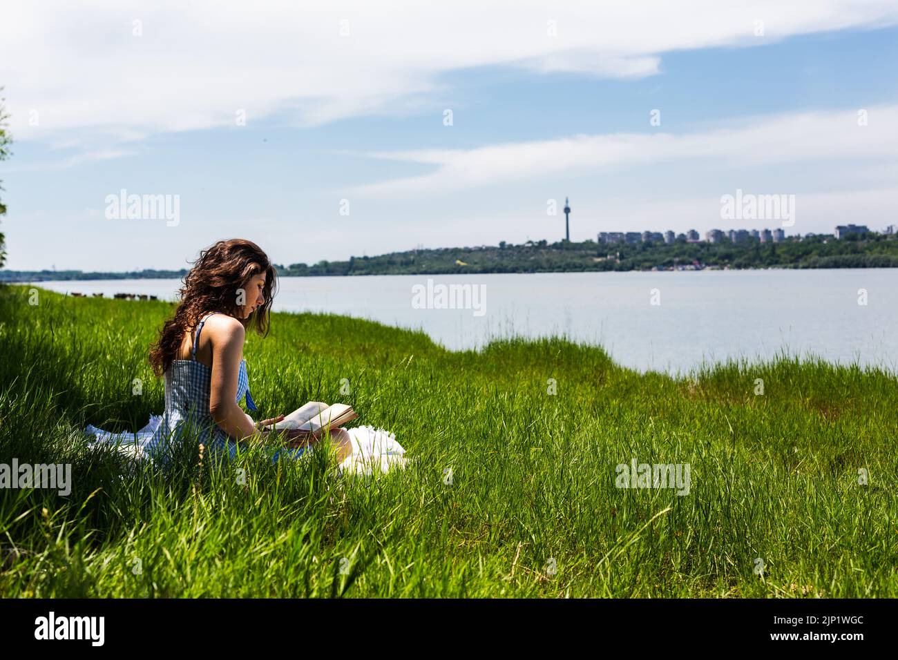 Beautiful young women reading a book sitting on the grass Stock Photo ...