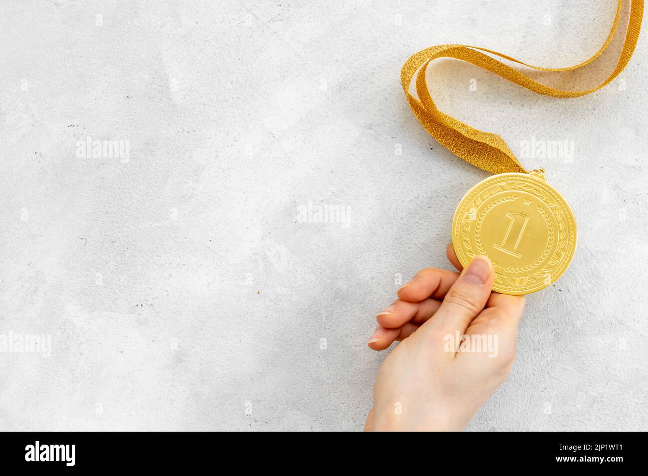 Hand holding up gold medal first place. Winner concept Stock Photo - Alamy