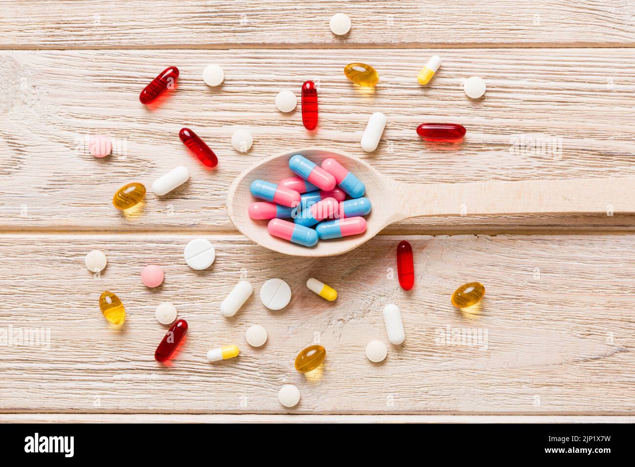 Vitamin capsules in a spoon on a colored background. Pills served as a ...