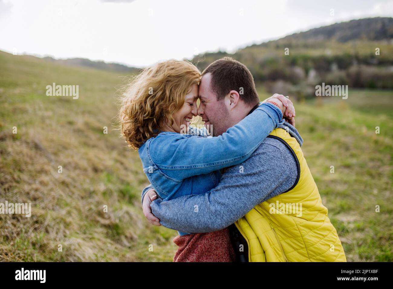 Outdoor portrait of mother hugging her grown up son with Down syndrome ...