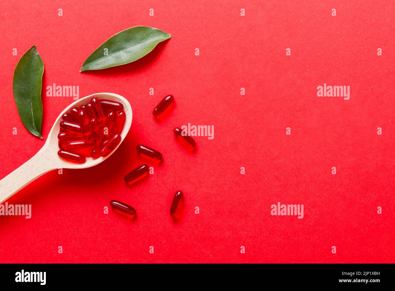 Vitamin capsules in a spoon on a colored background. Pills served as a ...