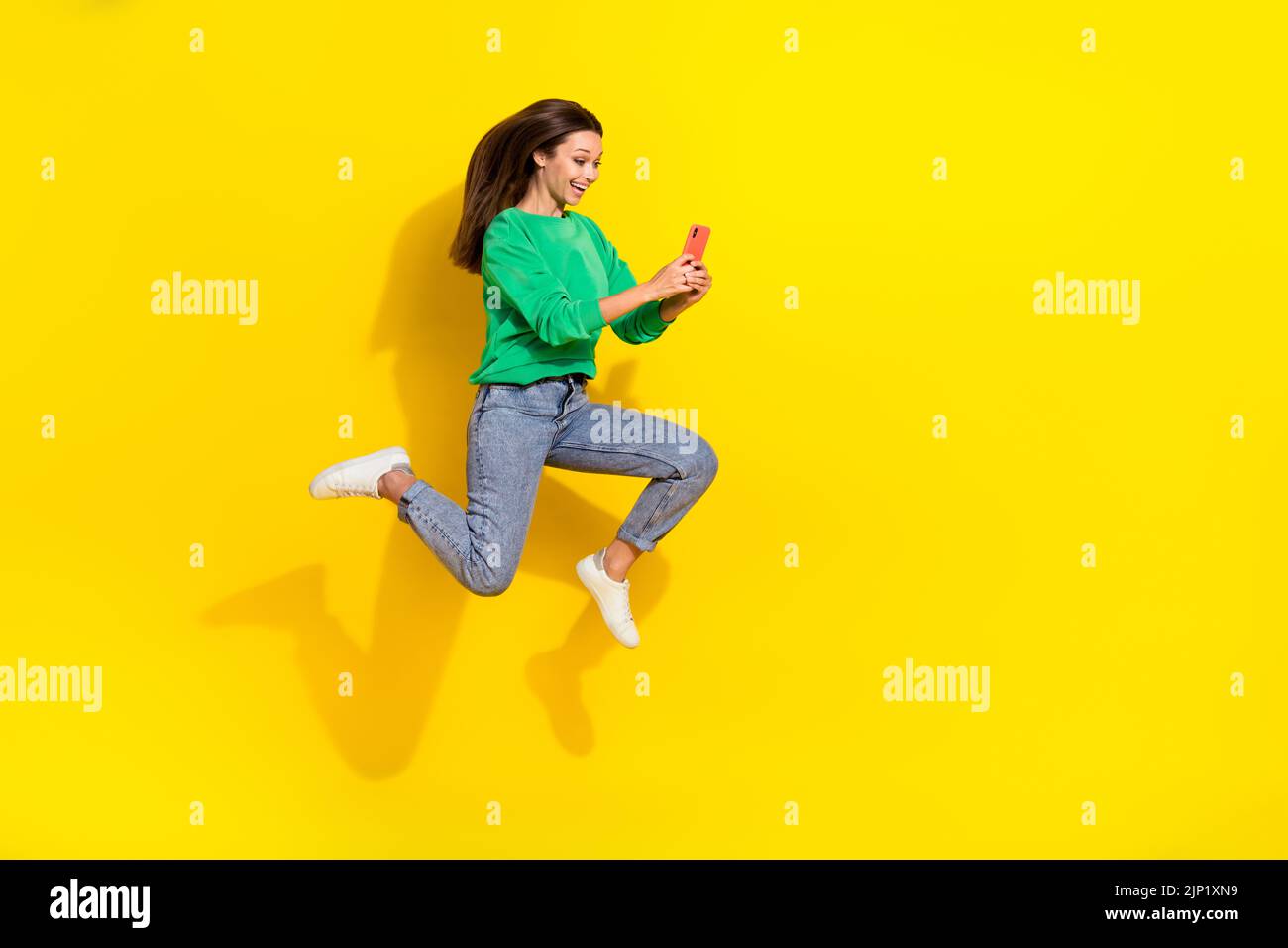 Full size portrait of energetic pretty girl jumping hold use telephone ...