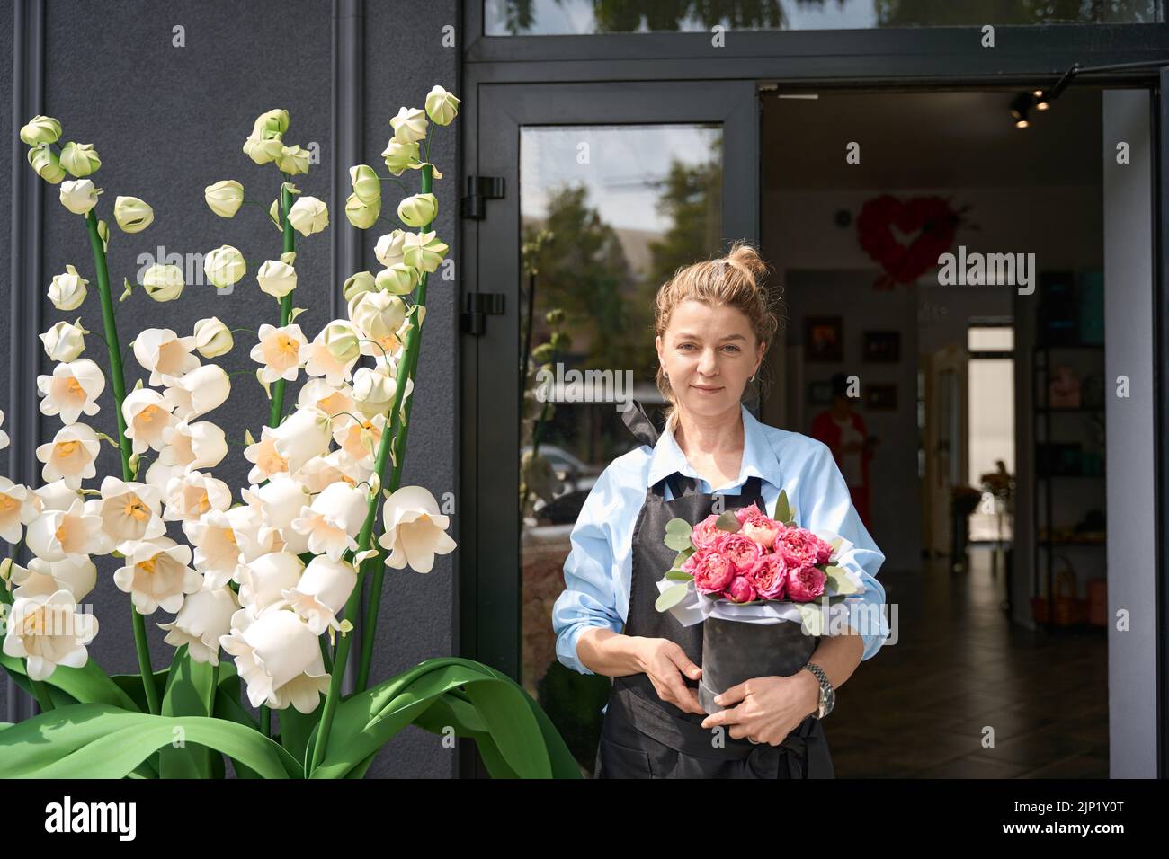 Portrait of cute female florist with bouquet of peony roses Stock Photo ...