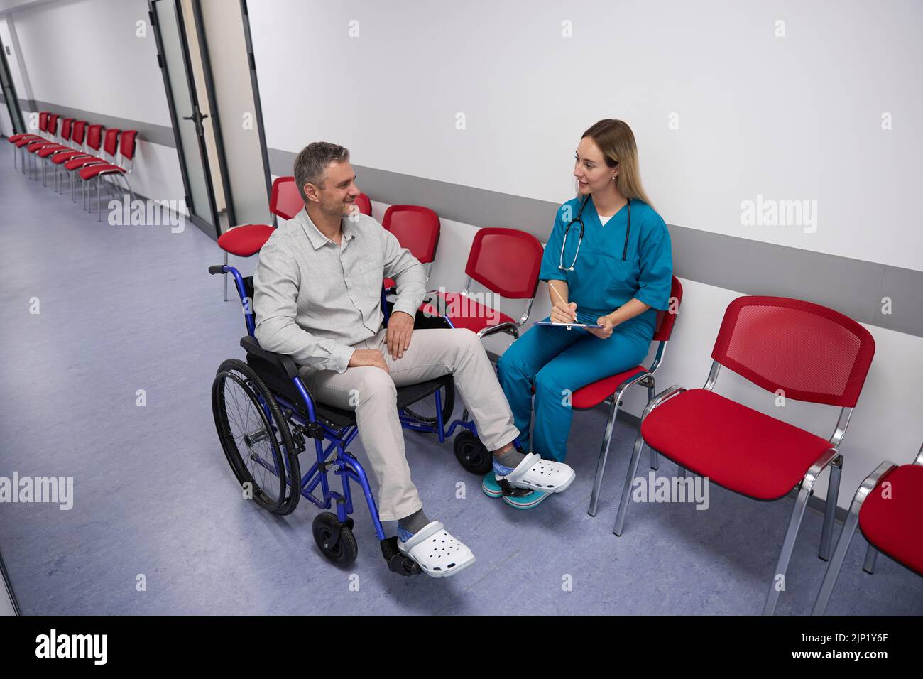 Optimistic patient in a wheelchair communicates with a friendly ...