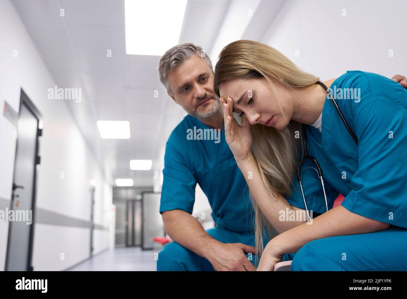 Doctor consoles a woman colleague in the corridor of the hospital ...